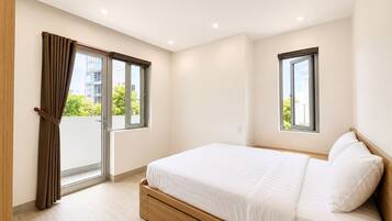 Quarto moderno com uma cama grande, portas de vidro deslizantes e vista para o verde lá fora.