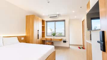 Quarto de hotel moderno com uma cama grande, uma mesa de escritório com cadeira, uma janela com vista e um ar condicionado.