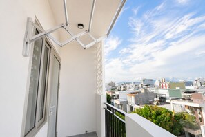 Uma varanda com vista para a paisagem urbana, uma janela e uma estrutura de metal.
