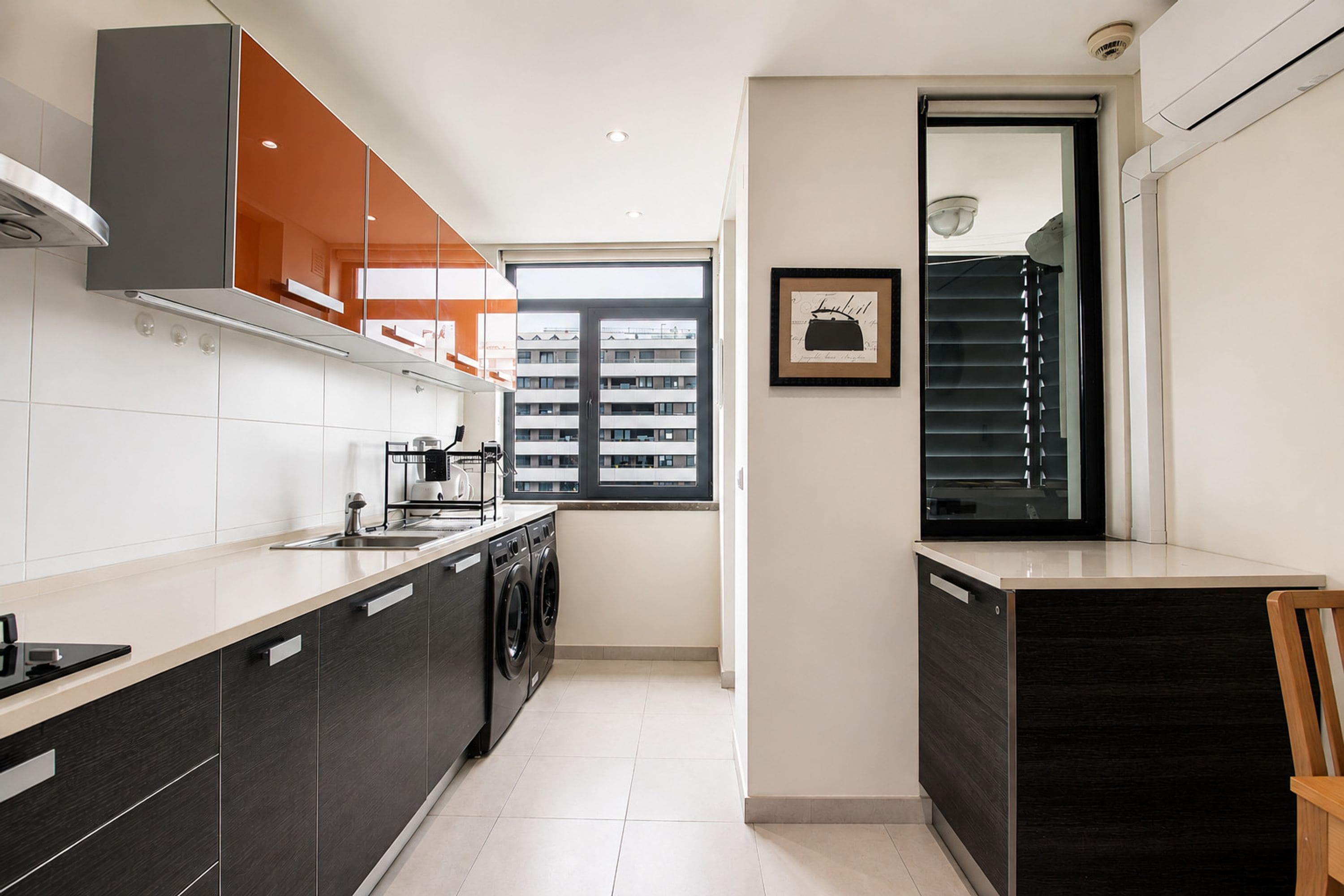 Cozinha moderna com forno embutido, máquina de café e janela com vista para um edifício.