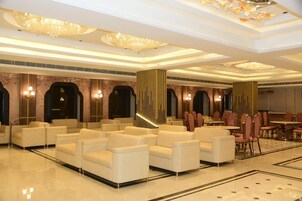 Um hall de hotel espaçoso com assentos confortáveis, lustres e piso lustroso.