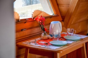 Uma mesa de madeira com um tapete, um vaso com flores vermelhas, um jarro branco e copos.