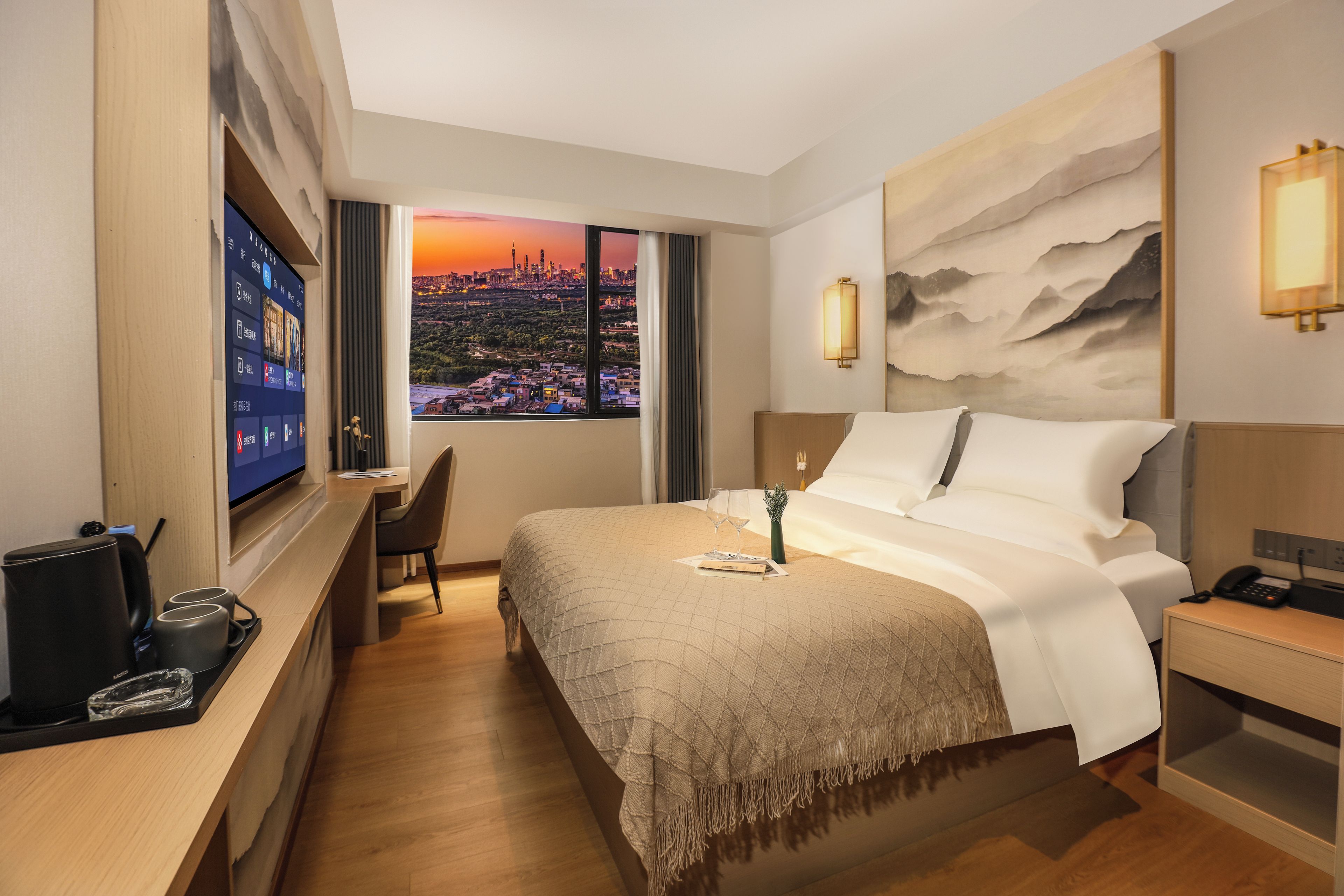 Quarto de hotel com cama, escrivaninha, cadeira, televisão e janela com vista para a cidade.