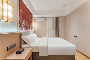 Quarto de hotel com cama, mesa de cabeceira, ar condicionado fixado na parede e um objeto decorativo na parede.
