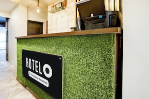 Bancada de recepção de hotel com sinalização indicando ser um hotel de serviço empresarial.
