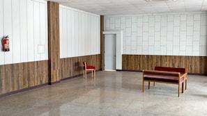 Um corredor com parede de painel de madeira, um extintor de incêndio, um banco e uma porta.