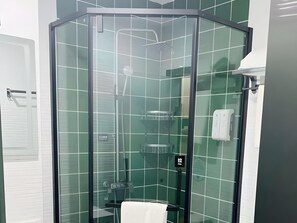 Box de chuveiro fechado por vidro com uma toalha branca pendurada na porta.