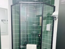Box de chuveiro fechado por vidro com uma toalha branca pendurada na porta.