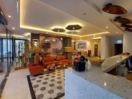 Um hall de hotel moderno com área de estar, balcão de recepção e uma grande janela.