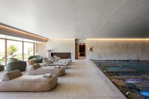 Uma área de spa com piscina, espreguiçadeiras e vista para o exterior.