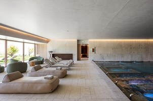 Uma área de spa com piscina, espreguiçadeiras e vista para o exterior.