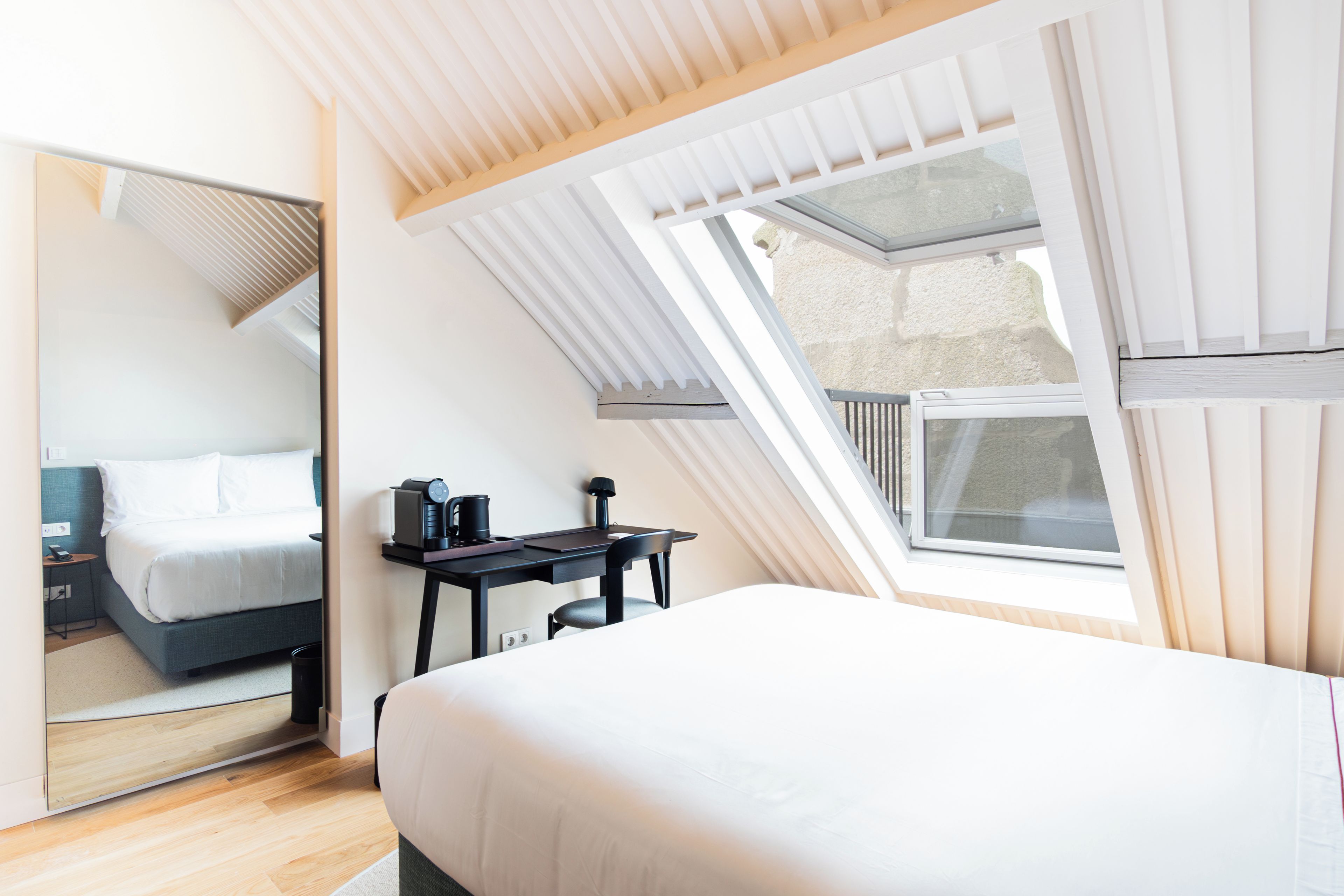 Quarto com uma cama, uma escrivaninha e uma janela com vista para o exterior.