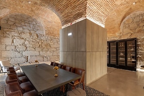 Uma sala de conferência com uma mesa comprida, cadeiras de couro e uma parede de pedra.