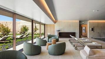Uma área de estar moderna com assentos, lareira e vista para o exterior.