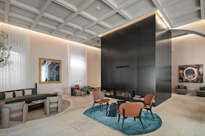 Uma sala de estar moderna com lareira, sofá, poltronas e obras de arte nas paredes.