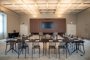 Sala de conferência com uma mesa comprida, cadeiras, TV de tela plana e lareira.