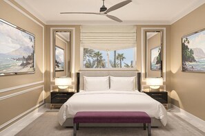 Quarto com cama grande, duas mesas de cabeceira, ventilador de teto e janela com vista para palmeiras.