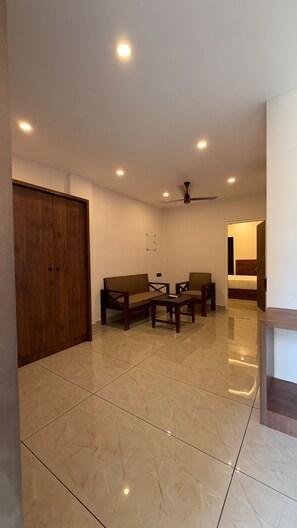 Quarto com guarda-roupa de madeira, sofá, mesa de centro e ventoinha no teto.