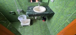Casa de banho com paredes de mármore verde, lavatório, sanita e zona de duche.