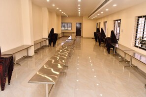 Um espaço comprido e estreito, com piso espelhado, fileiras de cadeiras e mesas ao longo das paredes.