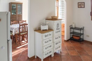 Uma cozinha com armário branco, mesa de jantar com cadeiras e janela com vista.