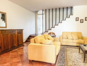 Uma sala de estar com escada, sofá, poltrona e armário.