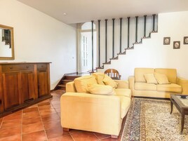 Uma sala de estar com escada, sofá, poltrona e armário.