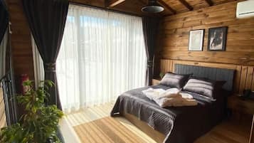 Quarto com painéis de madeira, uma cama, uma cadeira e uma planta.