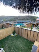 Uma área de piscina com cerca de madeira, uma pequena árvore e um edifício com uma placa.