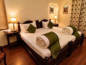 Quarto de hotel com uma cama grande, duas mesas de cabeceira com abajures e uma cadeira.