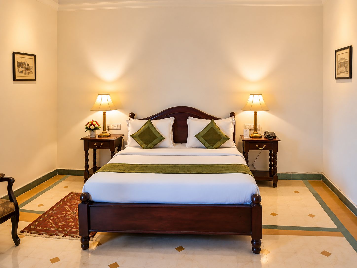 Quarto de hotel com cama grande, duas mesas de cabeceira com luminárias, cabeceira de madeira e tapete estampado.