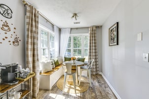 Um quarto acolhedor com piso de madeira, uma mesa redonda e um banco com almofadas.