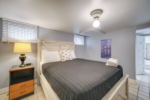 Quarto com cama, luminária de cabeceira e luminária no teto.