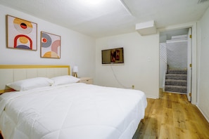 Quarto com cama, mesa de cabeceira, abajur e obras de arte na parede.