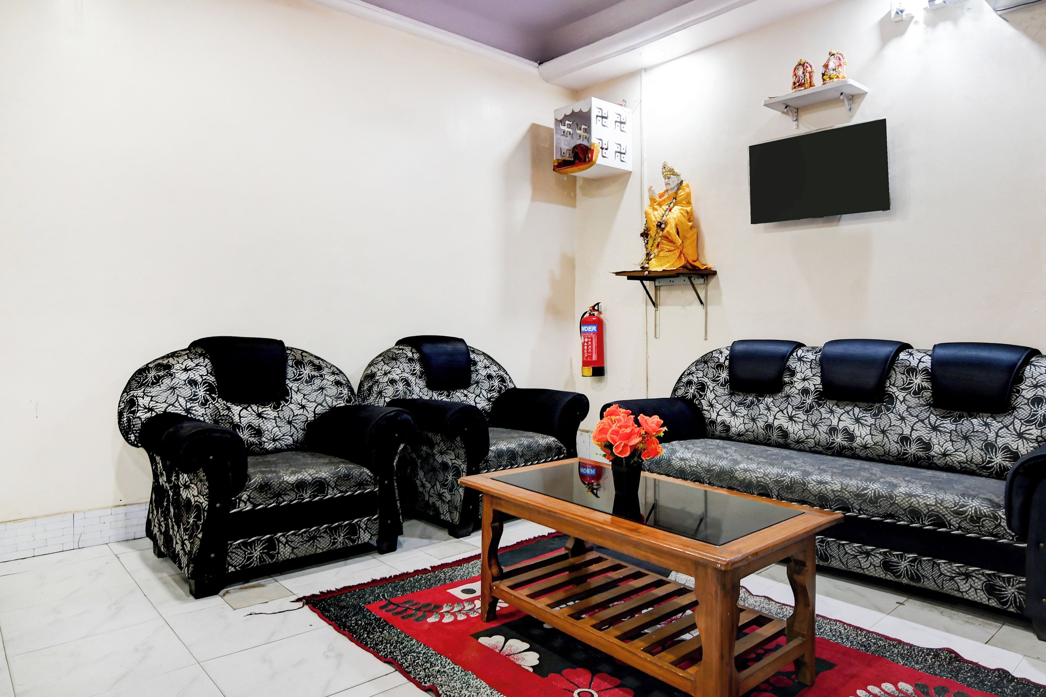 Sala de estar com dois sofás estampados, uma mesa de centro e um tapete vermelho e preto.