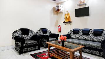Sala de estar com dois sofás estampados, uma mesa de centro e um tapete vermelho e preto.