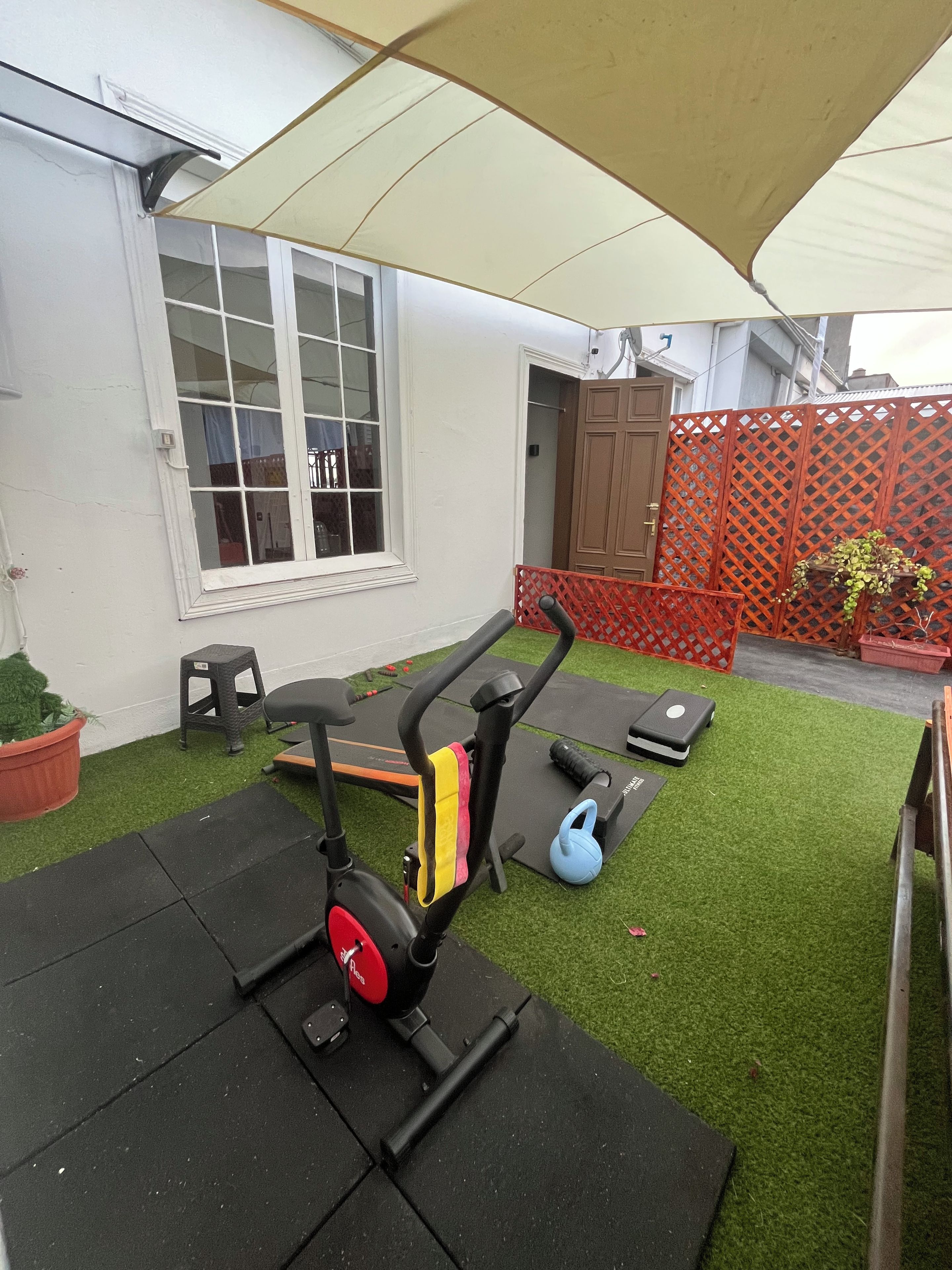 Espaço de ginástica em casa com equipamentos de exercício, uma janela e uma porta.