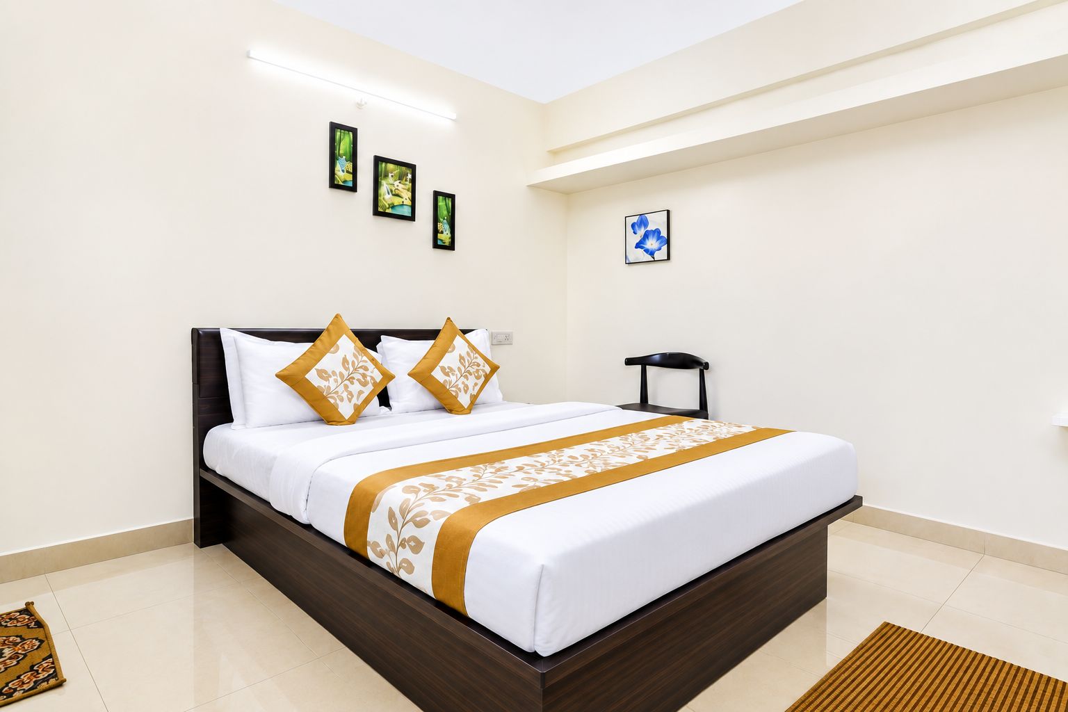 Quarto de hotel com cama, mesa de cabeceira, cadeira e obras de arte nas paredes.