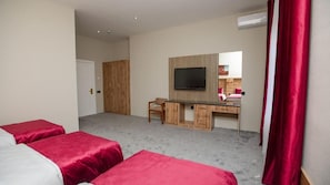 Quarto de hotel com cama, escrivaninha, televisão e guarda-roupa.