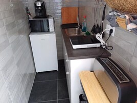 Uma cozinha compacta equipada com micro-ondas, torradeira e máquina de café.
