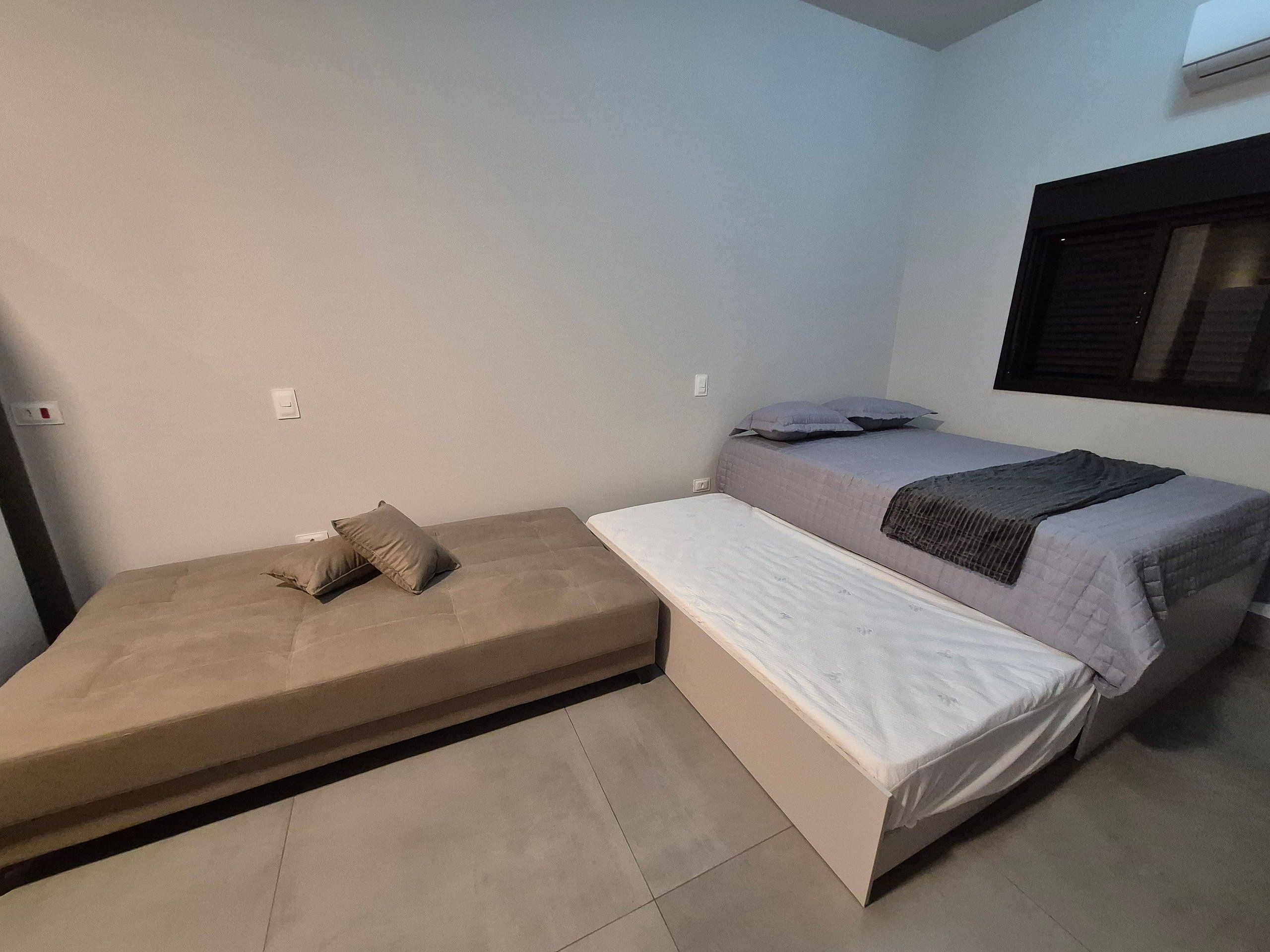 Acomodação compacta, com um quarto, cama, sofá e um banco.
