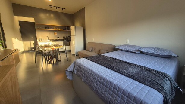 Quarto moderno com uma cama grande, um sofá e uma área de jantar com mesa e cadeiras.
