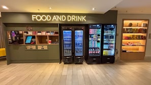 Quiosque de comida e bebidas com máquinas automáticas e um pequeno balcão.
