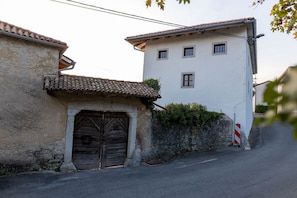Uma rua estreita com um edifício com telhado de azulejos tradicionais e uma grande porta de madeira.