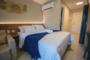 Quarto de hotel com cama, cadeira, ar condicionado e porta.