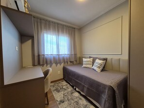 Quarto com cama, escrivaninha e cadeira.