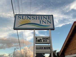 Placa do Sunshine Inn com design de sol e onda, indicando um tema praiano ou costeiro.