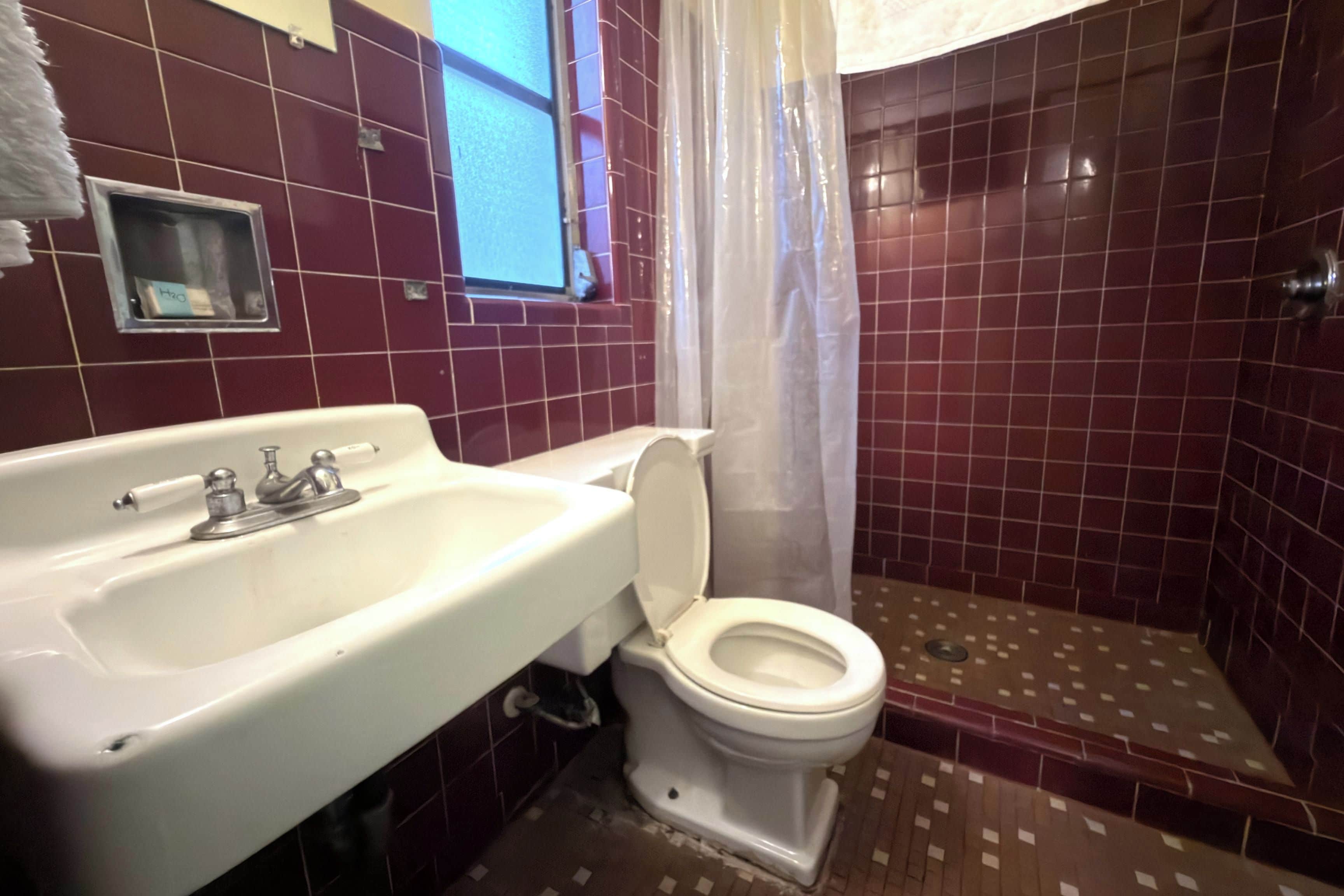 Casa de banho com lavatório branco, sanita e zona de duche.
