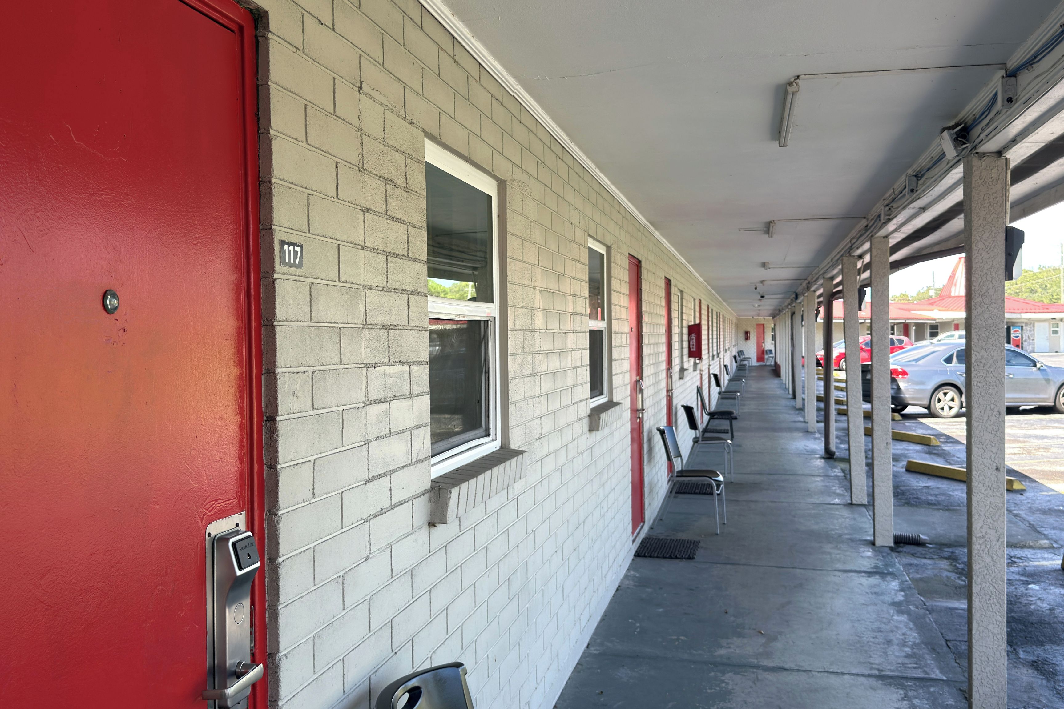Uma fileira de quartos de motel, com uma porta vermelha e janela no primeiro quarto.