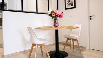 Uma sala de jantar moderna com uma mesa redonda, duas cadeiras brancas e um vaso com flores.